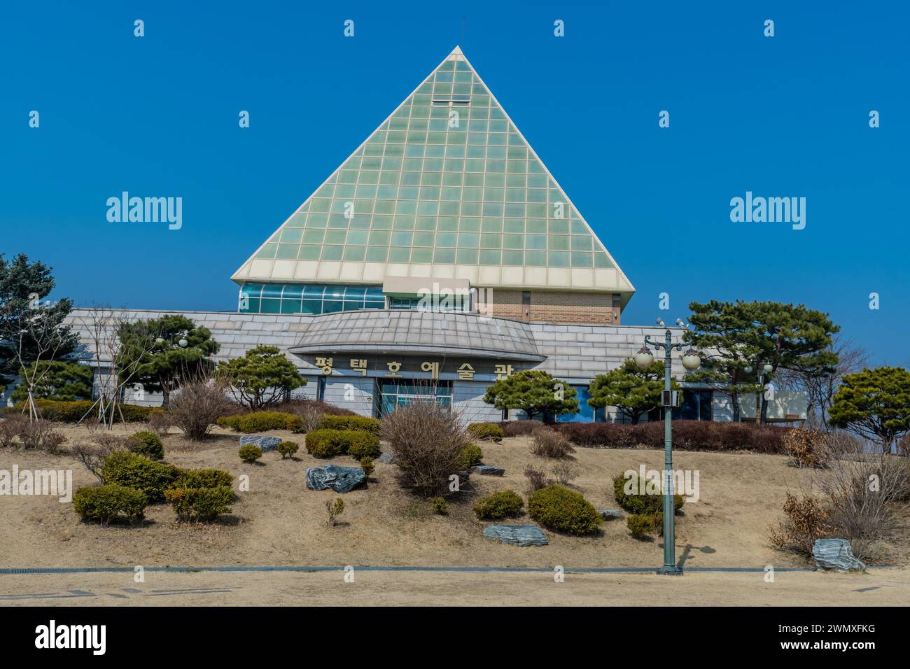 Art museum with triangular roof at lakeside park with trees in ...
