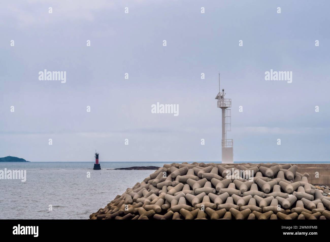 White light house on pier and red lighthouse on rocky point of small ...