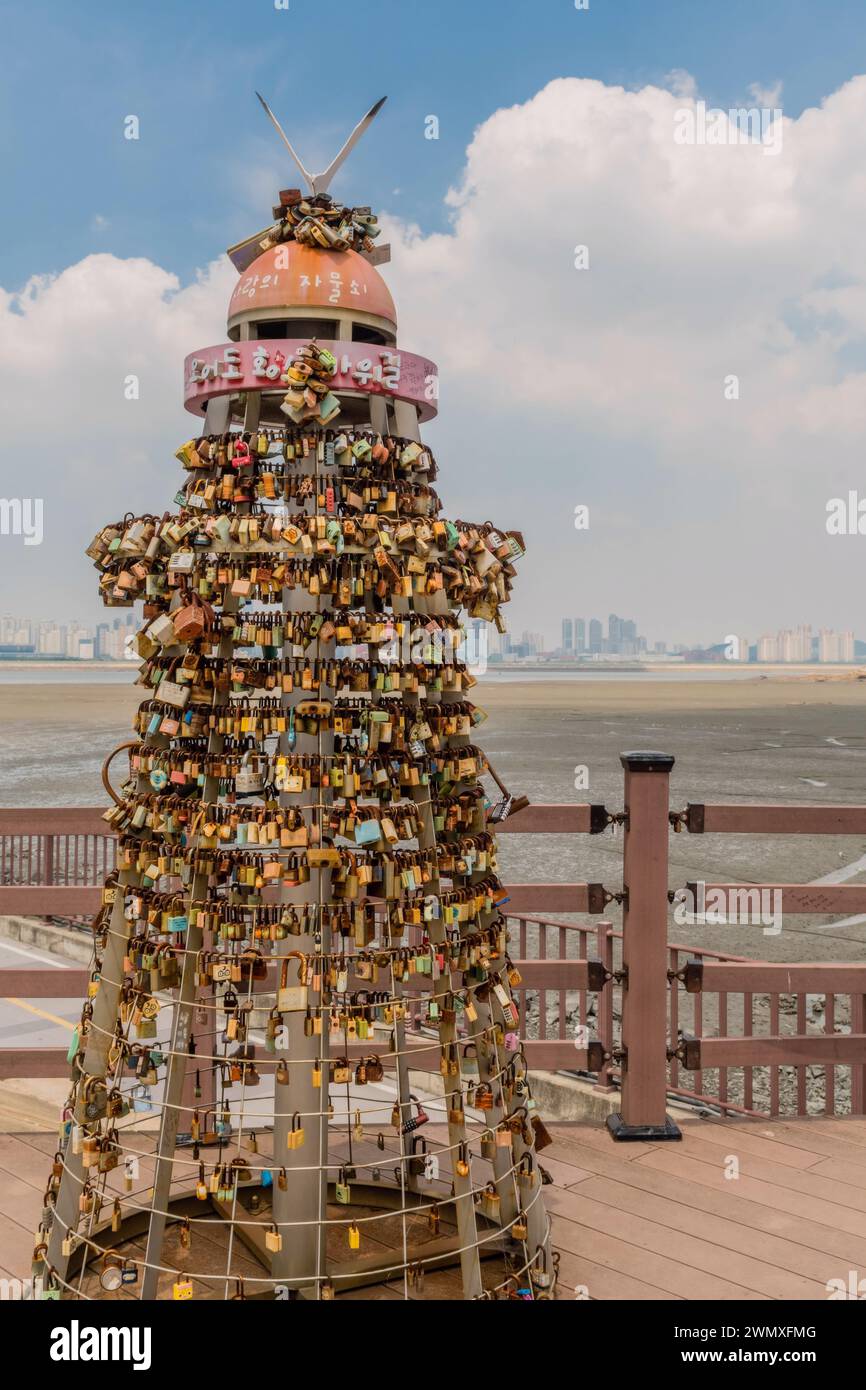 Padlocks on wire replica of red lighthouse on wooden deck at Oido port ...