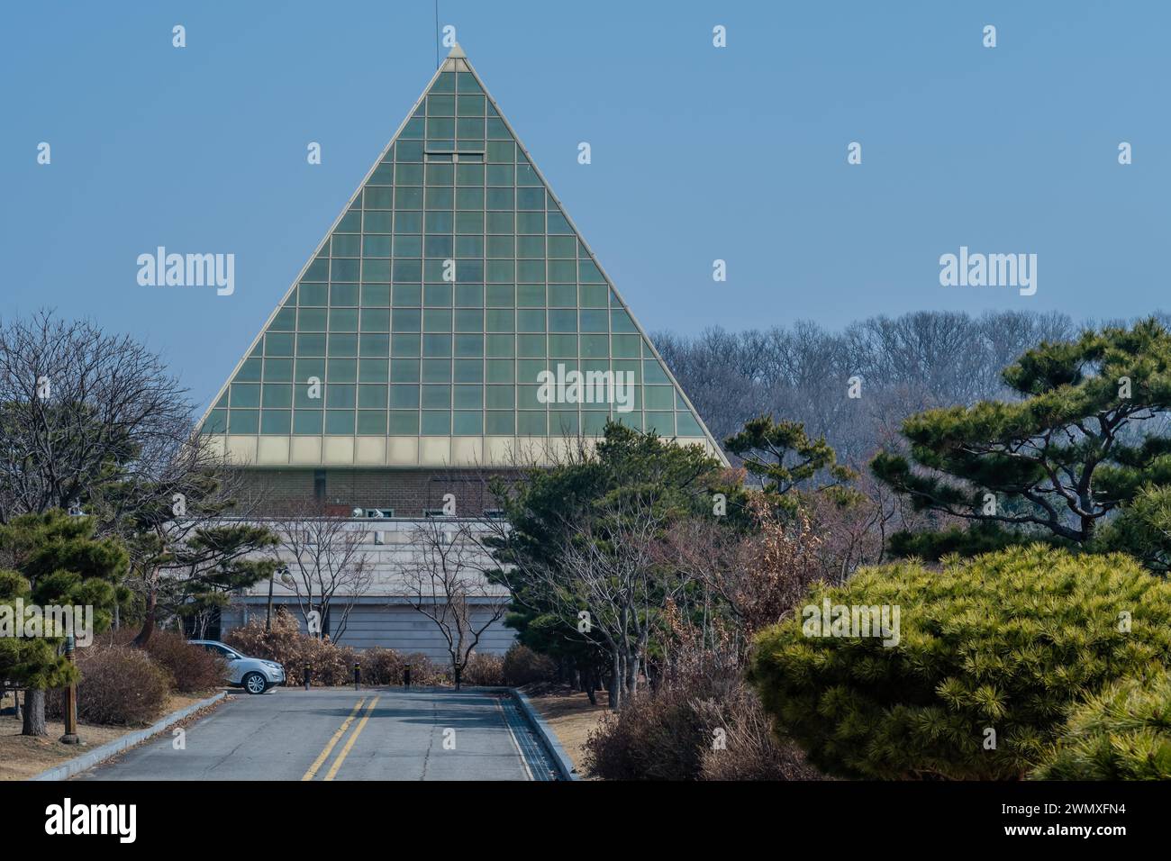 Triangular roof of art museum at lakeside park with trees in foreground ...
