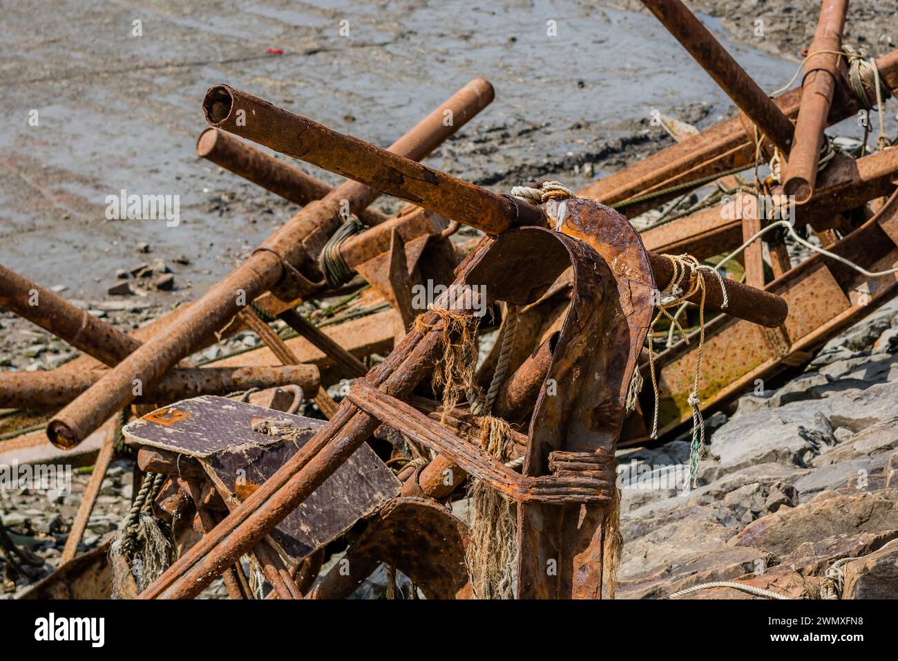 Large rusty ship anchors laying on side of seawall with water in ...