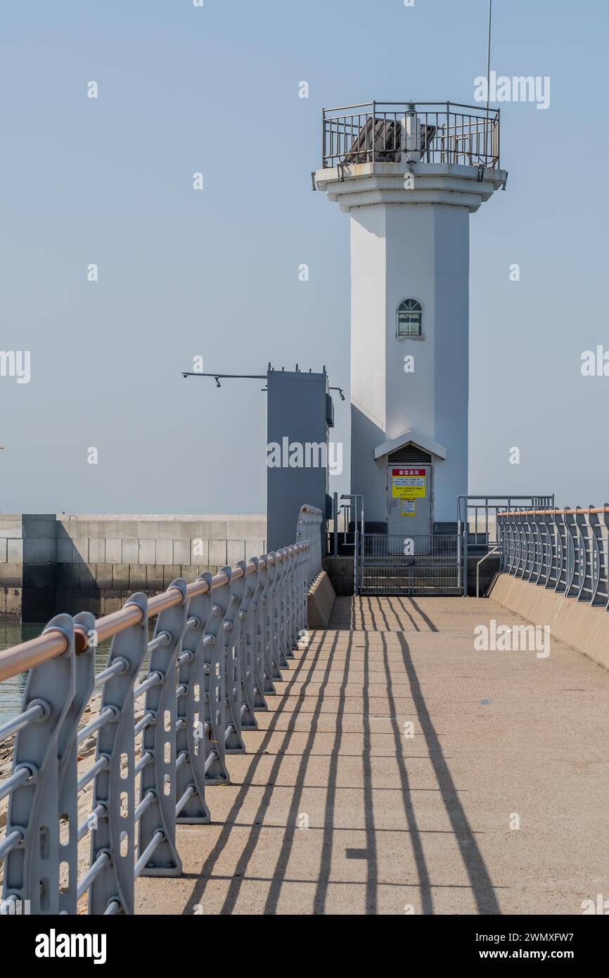 Small white lighthouse on end of concrete quay on overcast day in ...