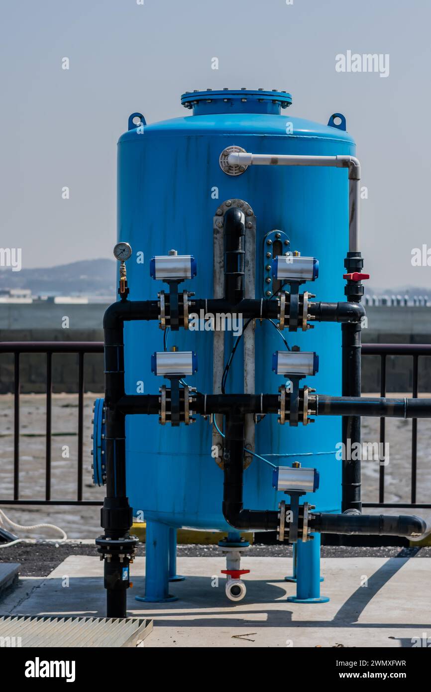 Blue water tank with gauges, valves and pipes outside on concrete ...