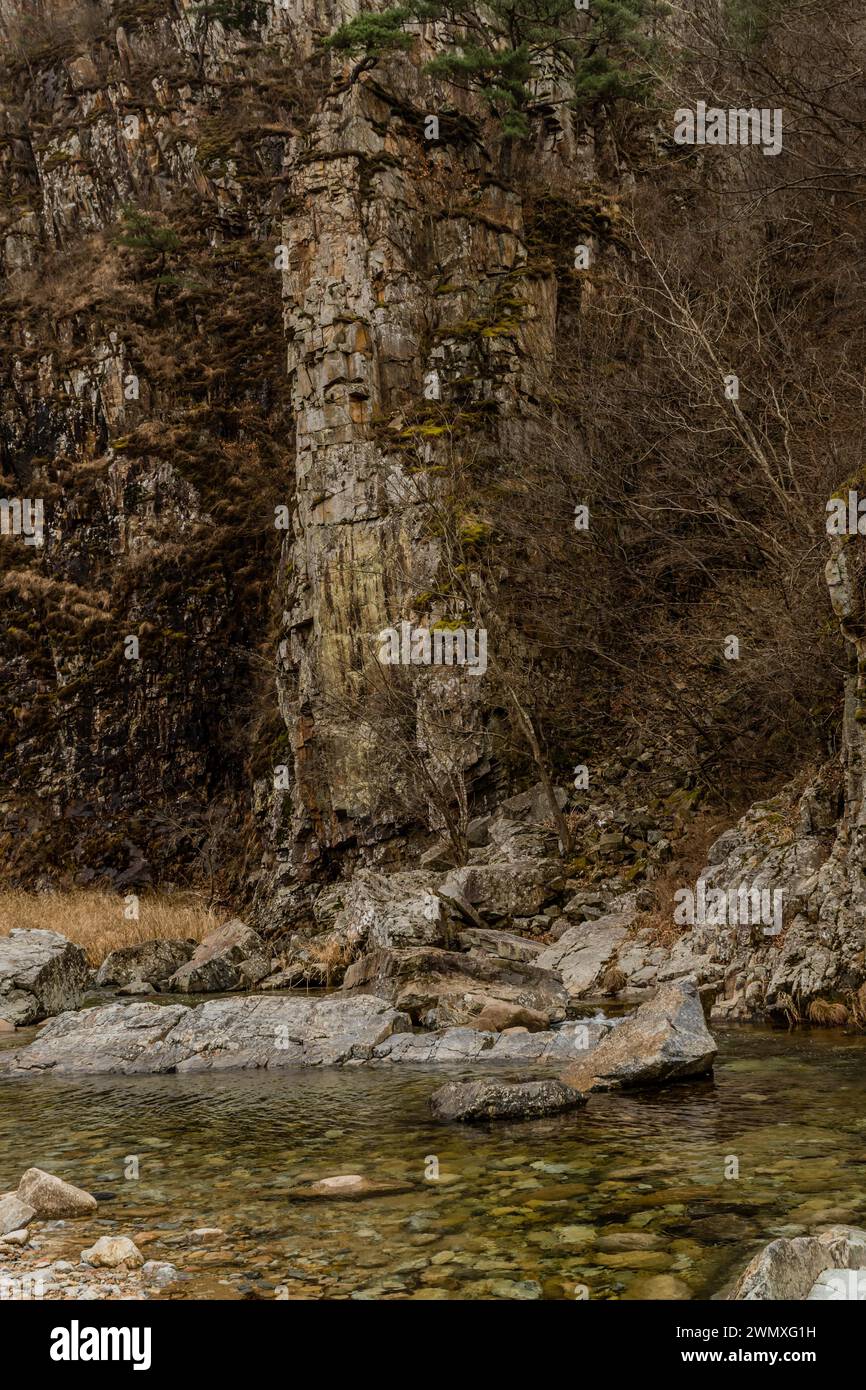 Large granite boulders in mountain stream with cliff face in background ...