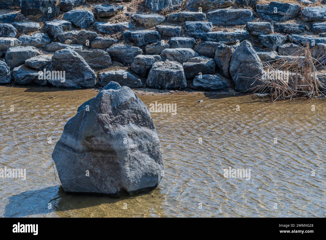 Large boulder in middle of shallow man made river in wilderness park ...