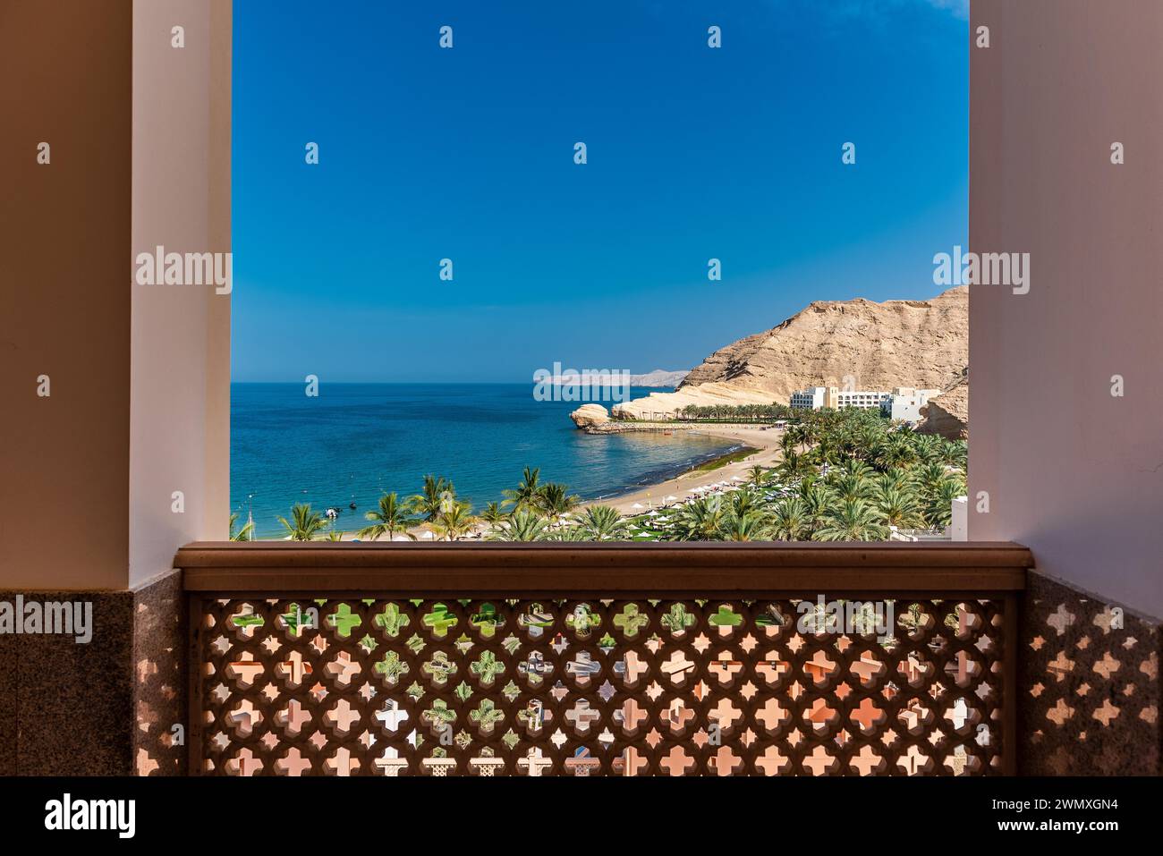 View of an idyllic sea coast with palm trees and cliffs from a terrace ...
