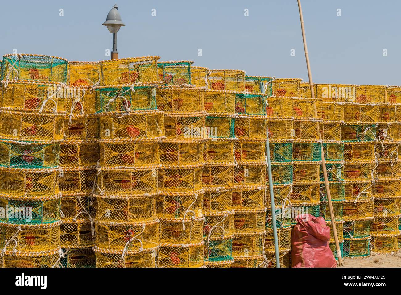 Round yellow crab and lobster nets stacked neatly at seaside marina in ...