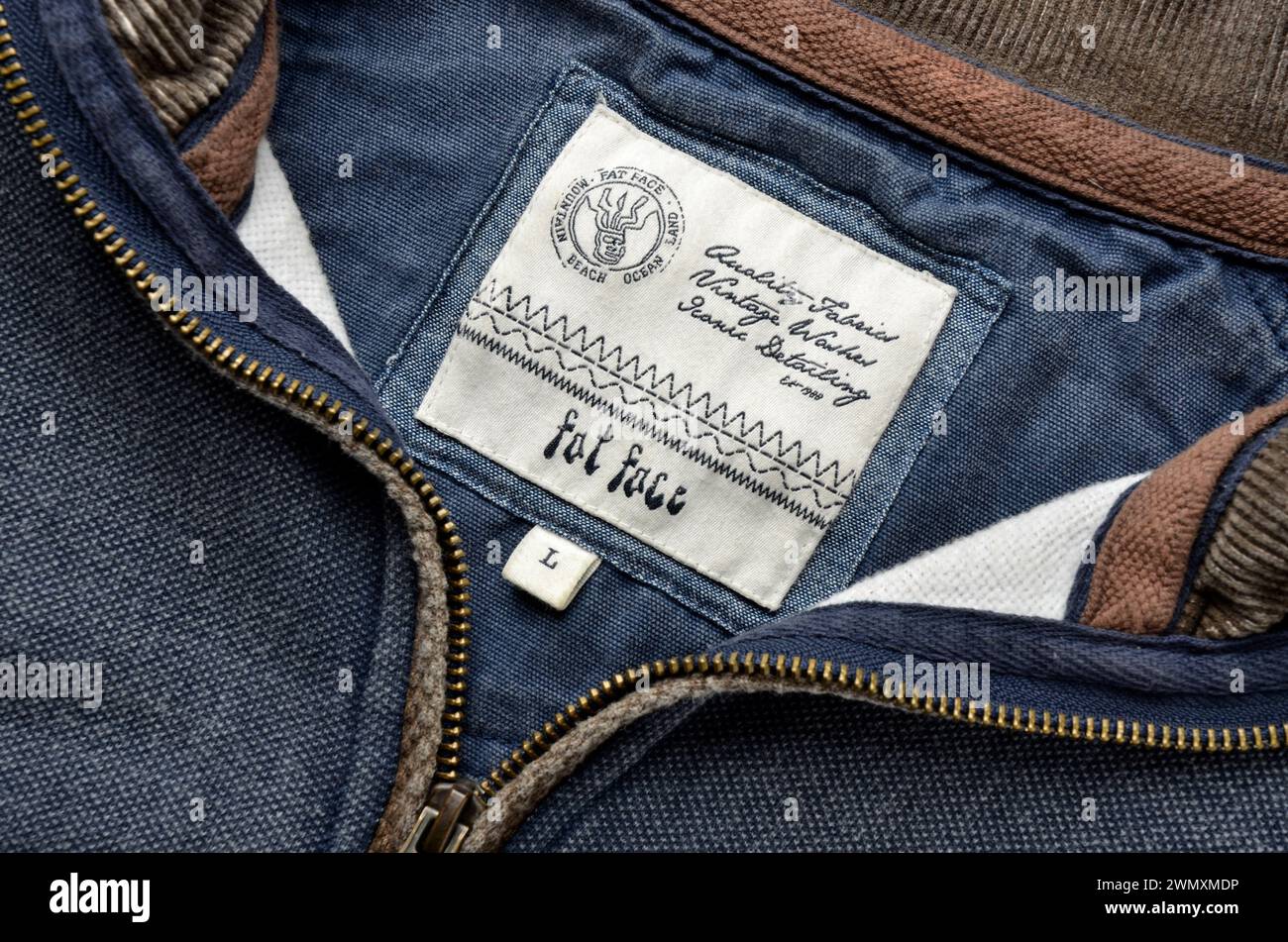Close up of Fat Face clothing brand label and zip on blue cotton ...