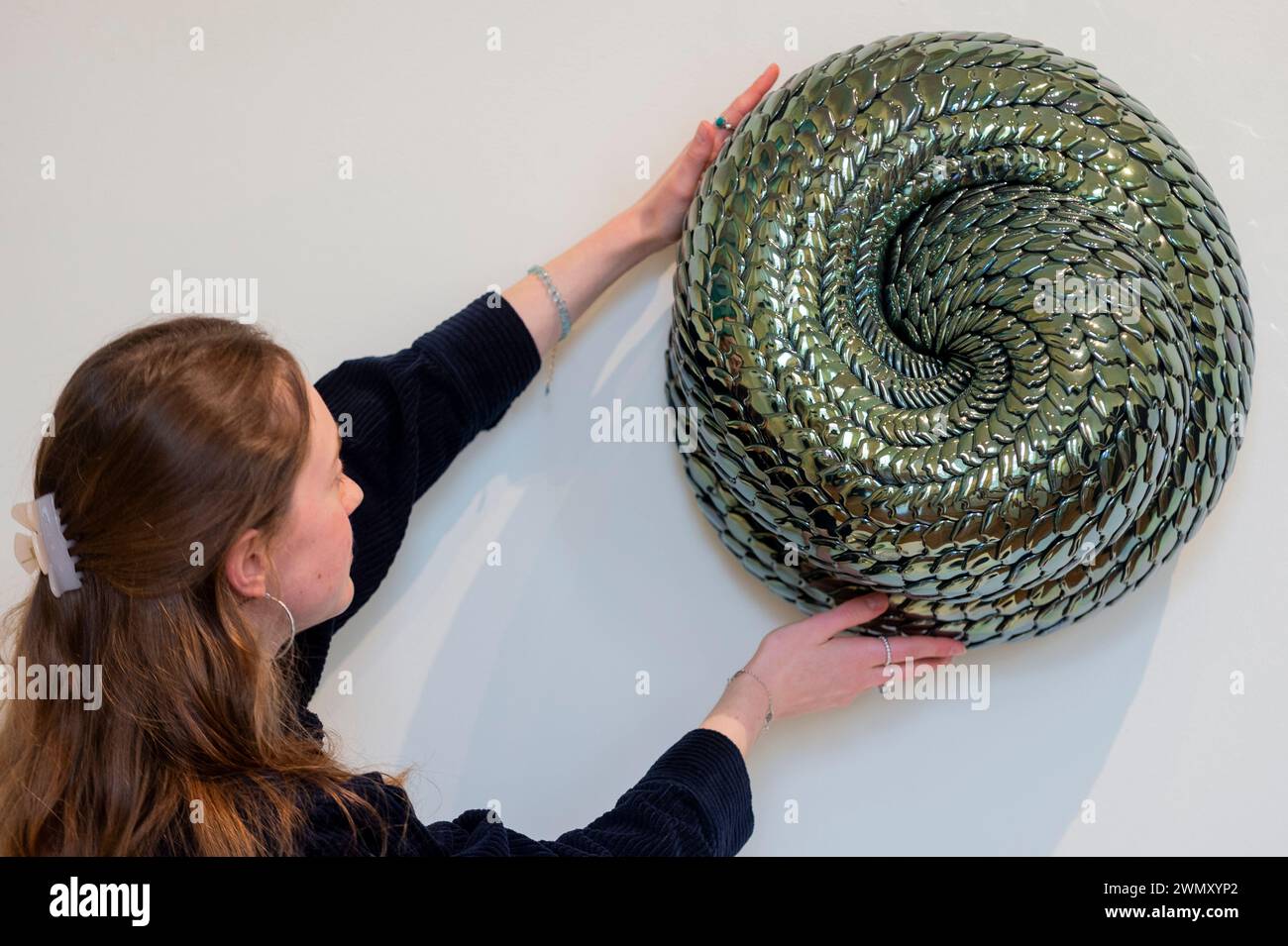 London, UK. 28 February 2024. A staff member with 'Green Ammonite' by ...