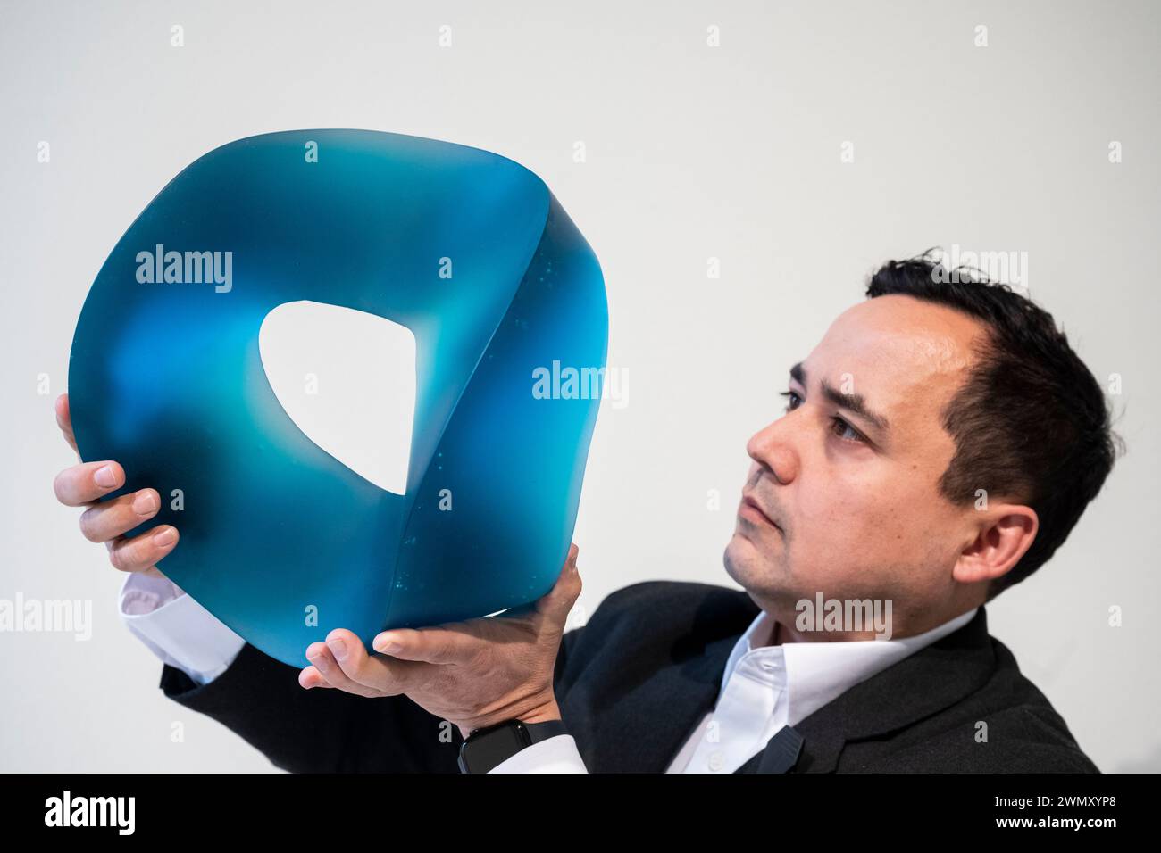London, UK. 28 February 2024. A staff member with cast glass work ...