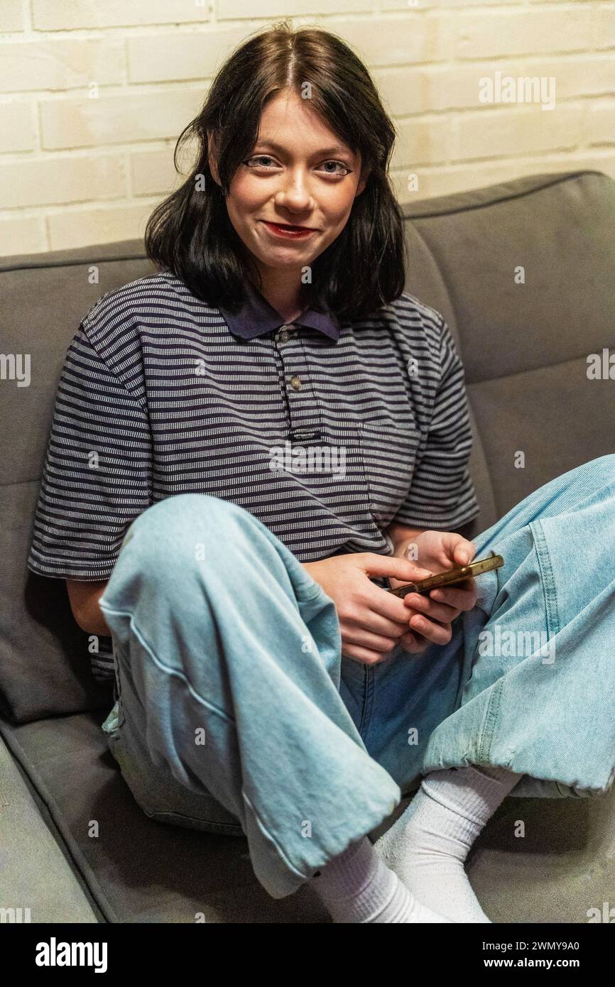 A beautiful and cheerful teenage girl from generation z is seated on ...