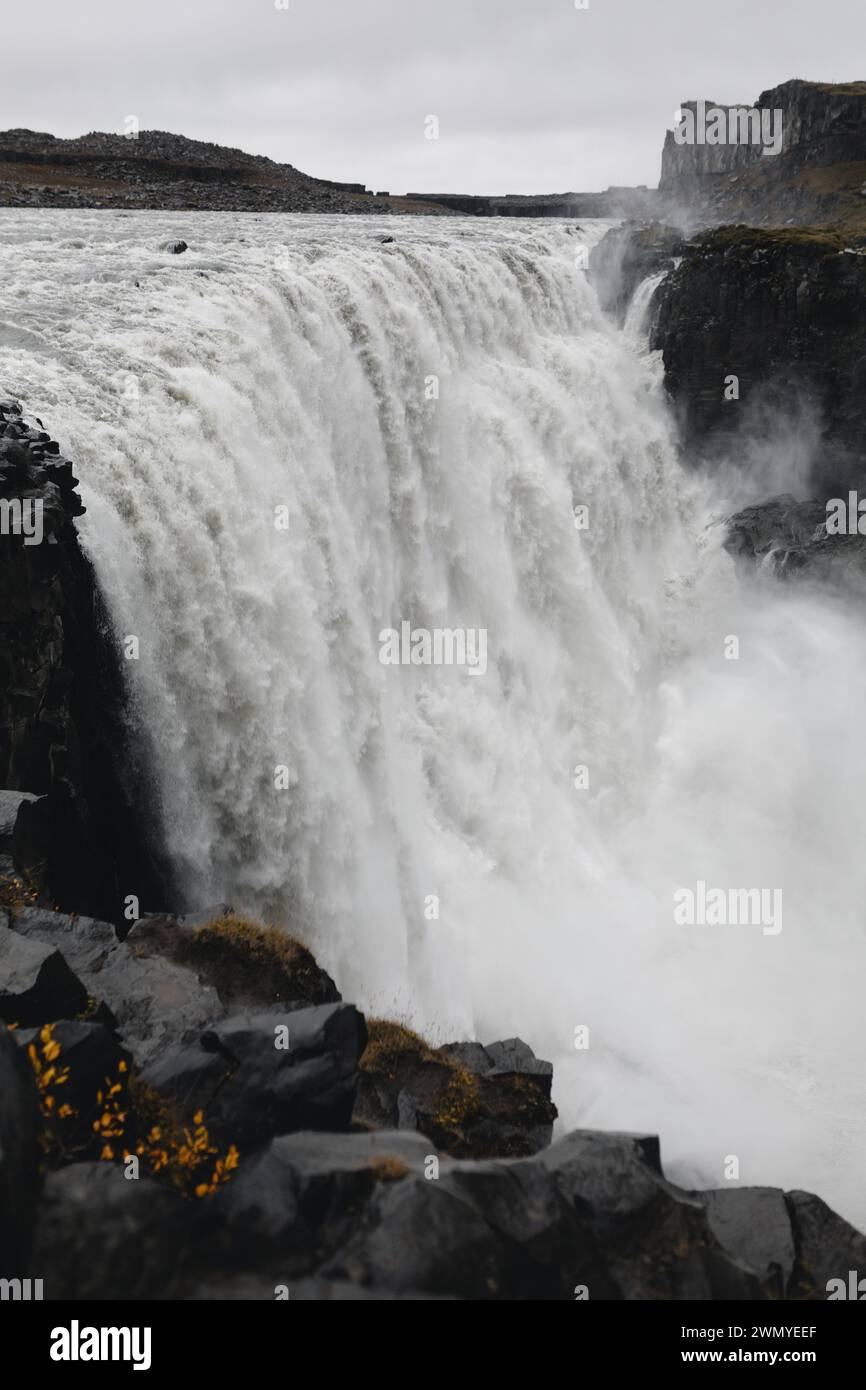 A powerful waterfall cascades down, surrounded by Iceland's stark and ...