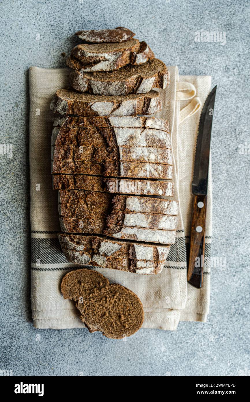 Top view of loaf of rye sourdough bread, partially sliced, with a bread ...