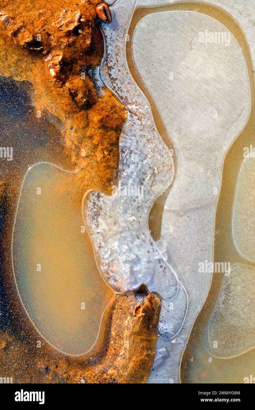 Aerial view of ice patterns with biofilm and rust-colored sediment in a ...