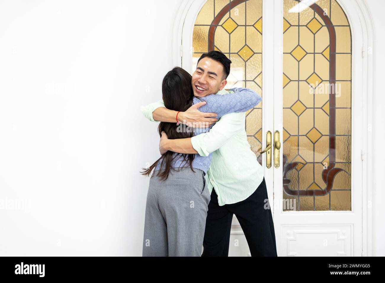 A smiling man and woman sharing a warm, heartfelt hug in front of a ...