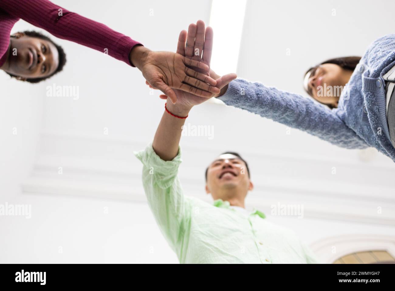 Diverse group of people stack hands together, signaling teamwork, unity ...