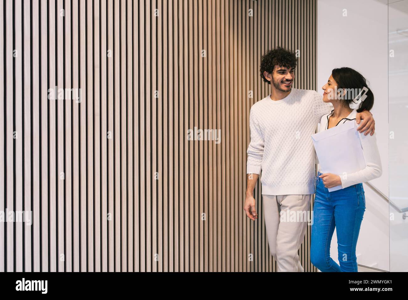 Two colleagues chatting in a modern office environment, one wearing ...