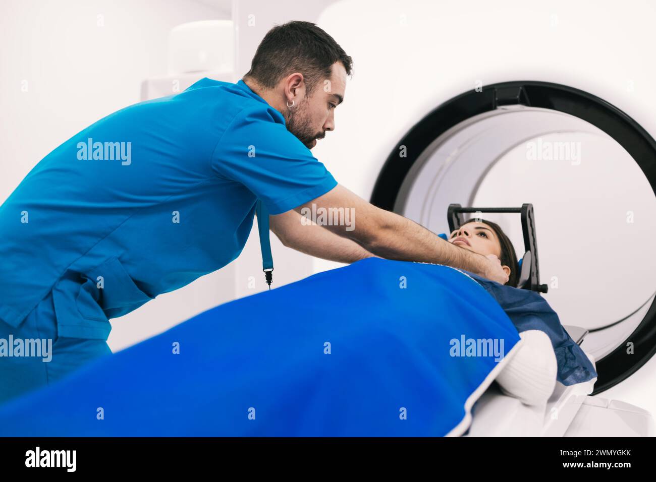 Male technician assisting a female patient before a computed tomography ...