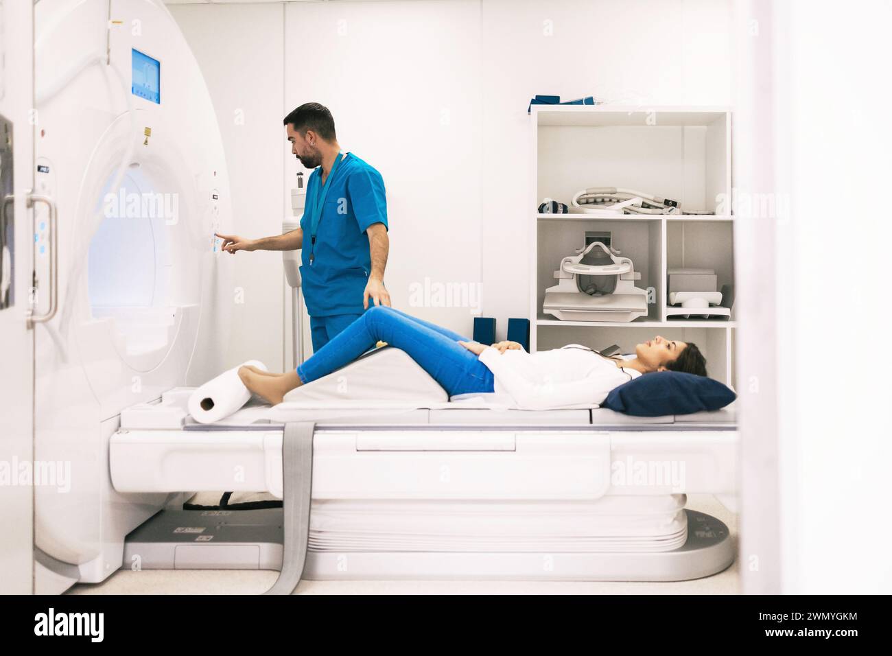 A healthcare worker is preparing an MRI scan for a female patient lying ...