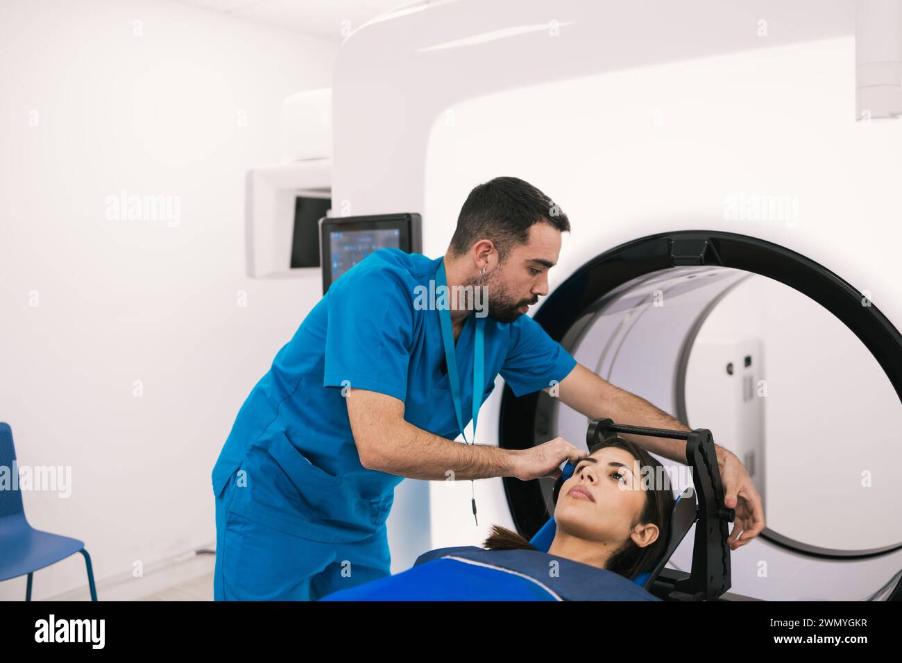 Male technician assisting a female patient before a computed tomography ...