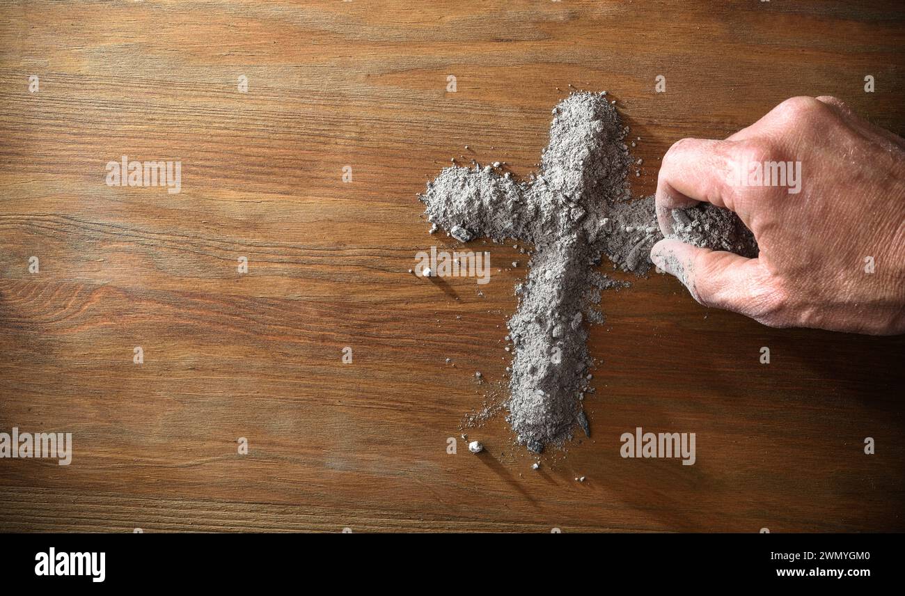 Hand making Christian cross symbol with ashes on wooden table. Top view ...