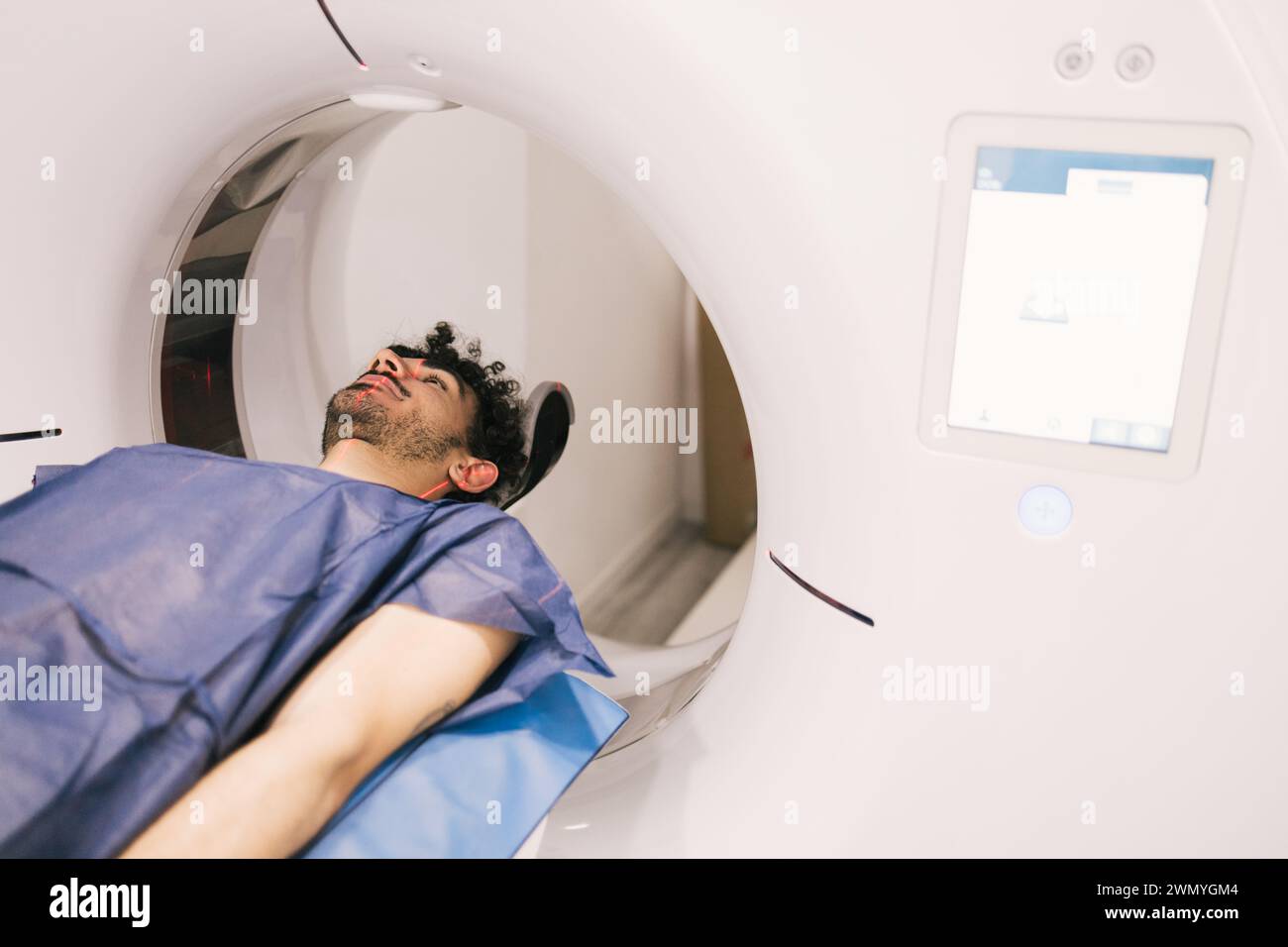 A male patient lies still in a CT scanner during a diagnostic ...