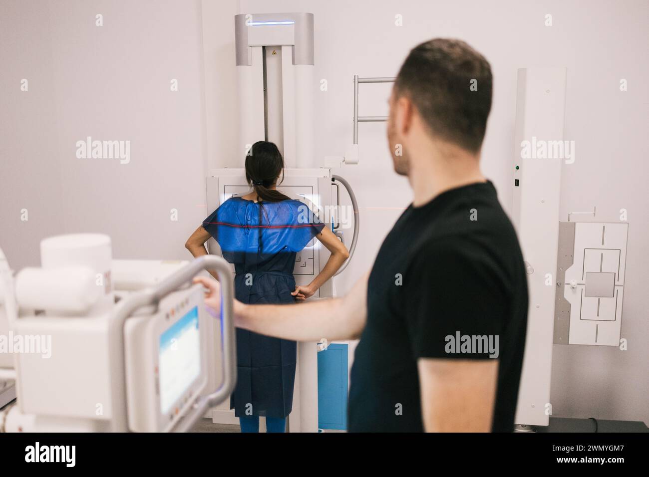 A patient wearing a protective lead apron prepares for an x-ray ...