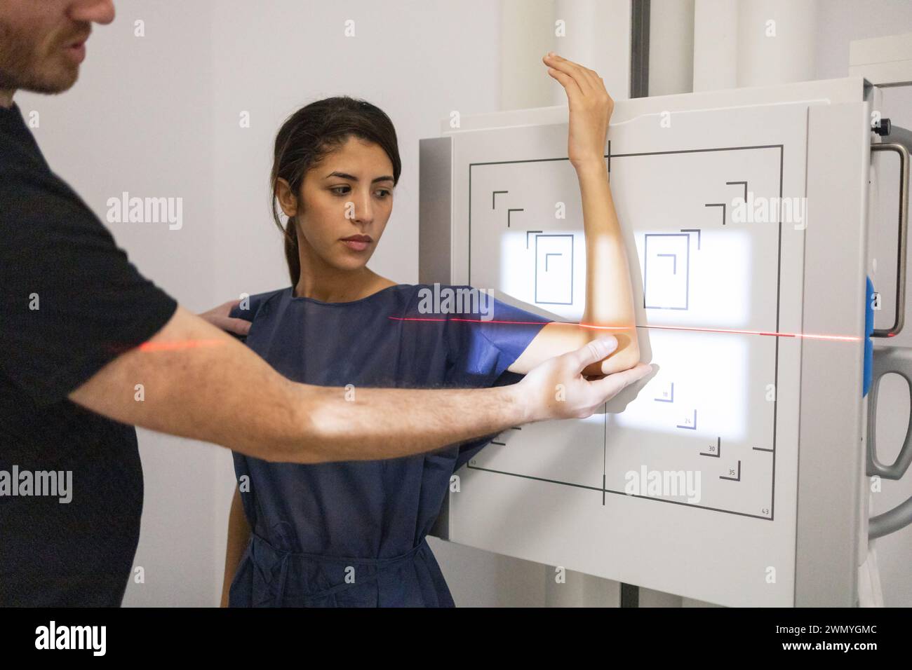 A technician assists a patient with positioning her wrist for a digital ...