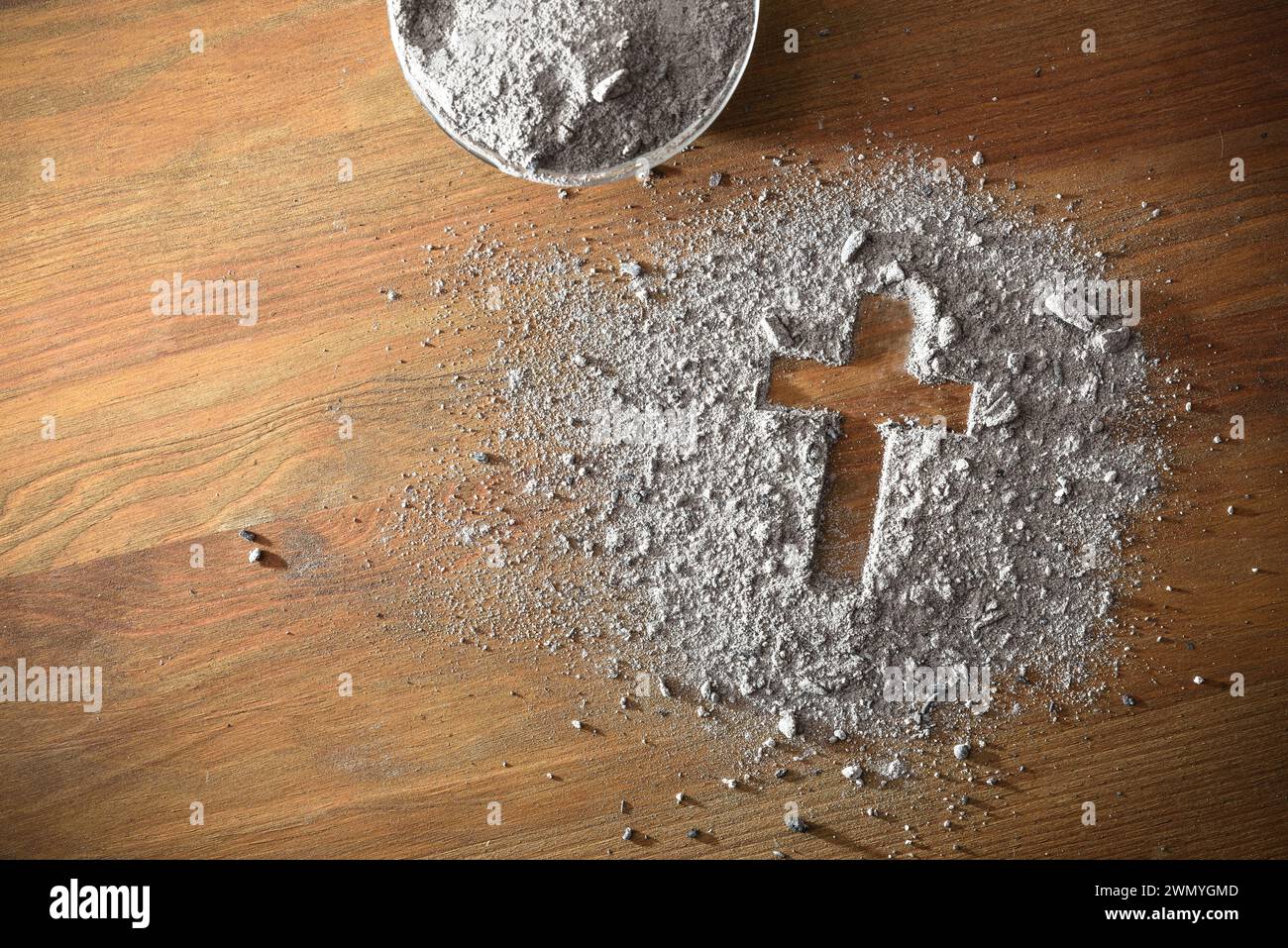 Ashes in glass container and scattered on wooden table with Christian ...
