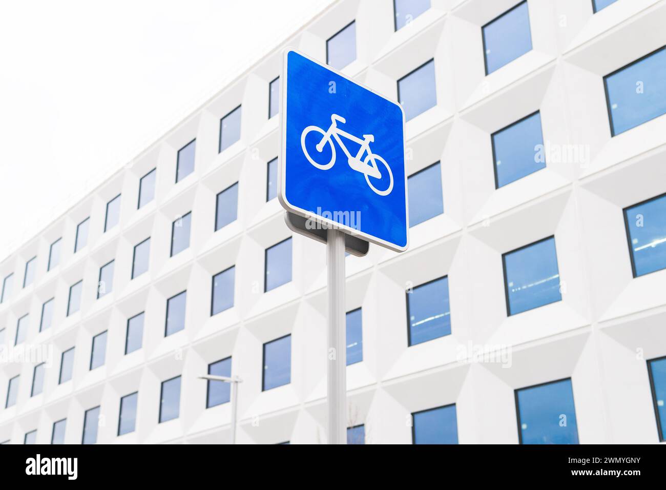 A bicycle lane sign prominently displayed in front of a modern building ...