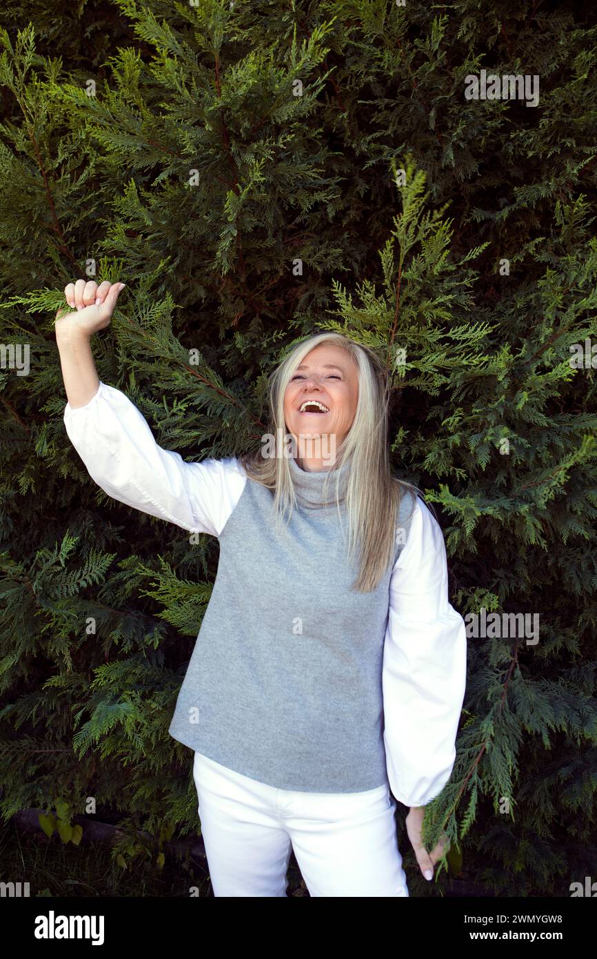Exuberant mature woman laughing and raising her fist in joy against a ...
