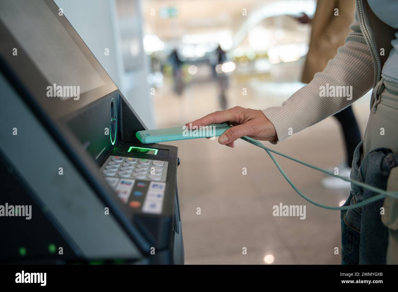 Back view of a woman using a contactless payment system at an airport ...