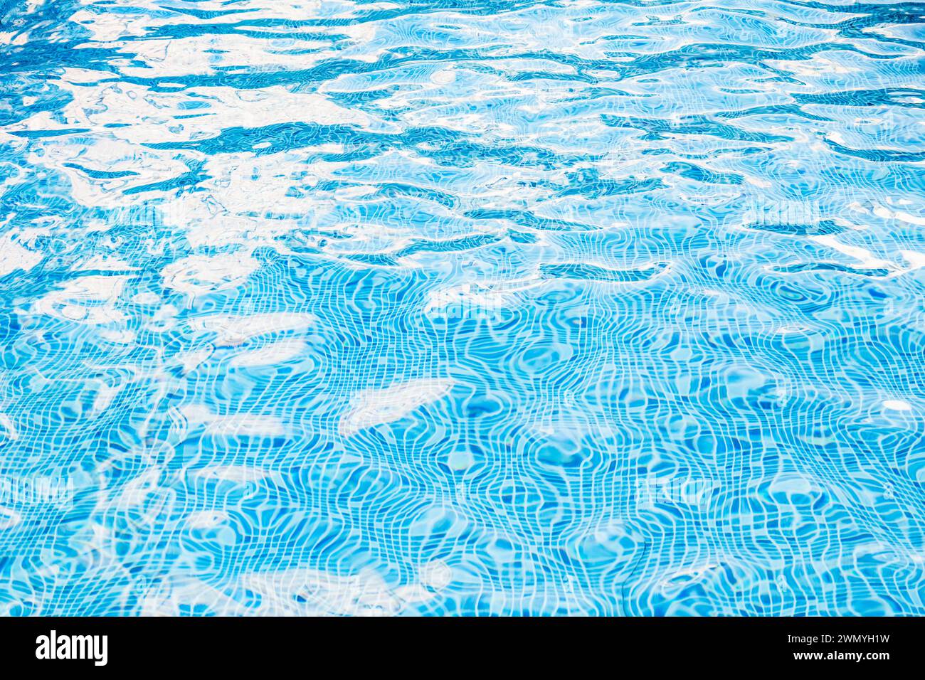 A close-up of crystal-clear swimming pool water shimmering under the ...