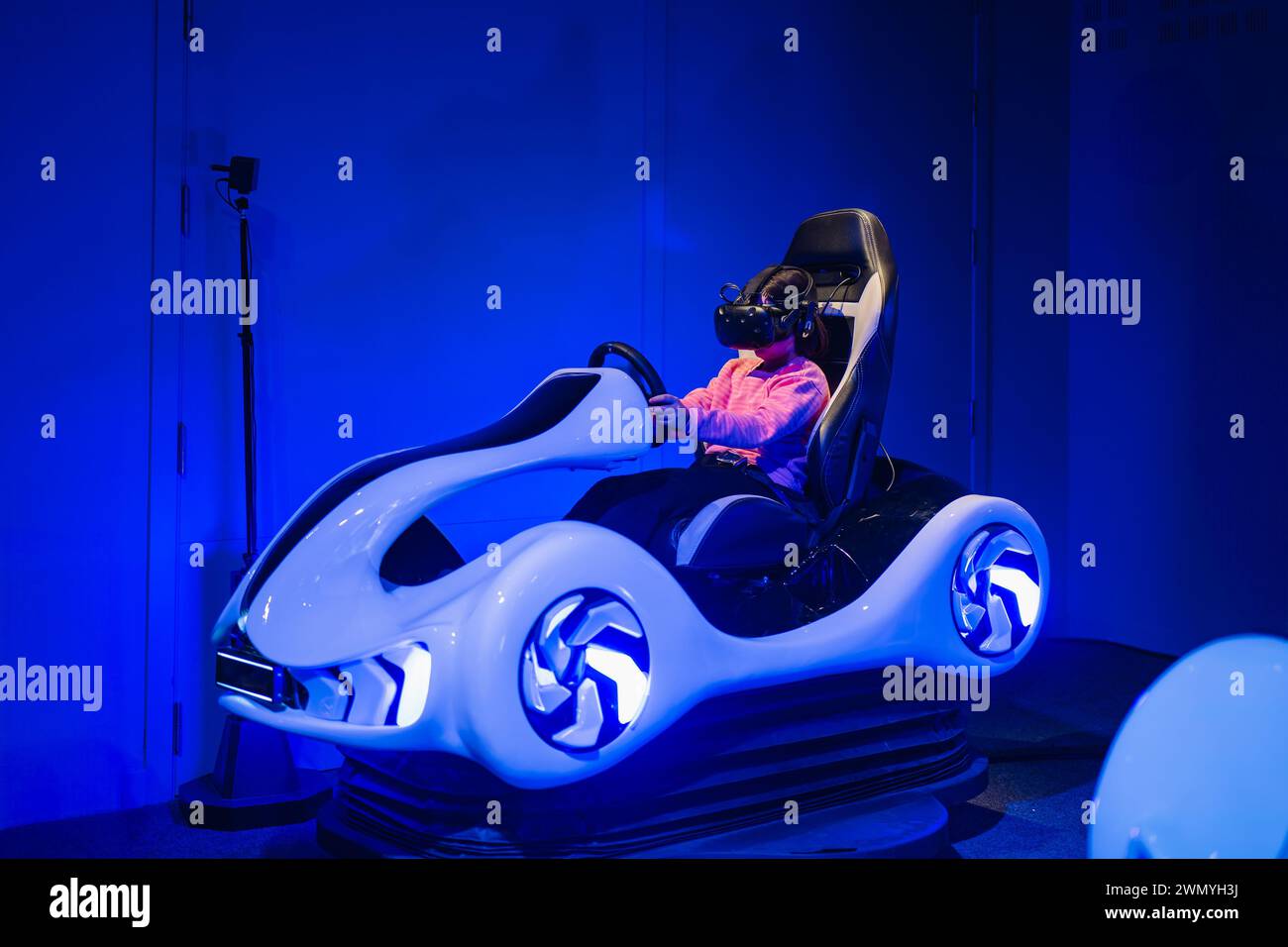 Child in a VR headset seated in a high-tech simulator with blue ...