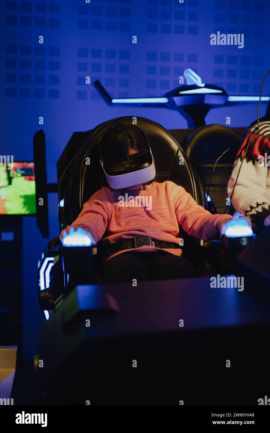 A child is absorbed in using a VR headset and controls while sitting in ...