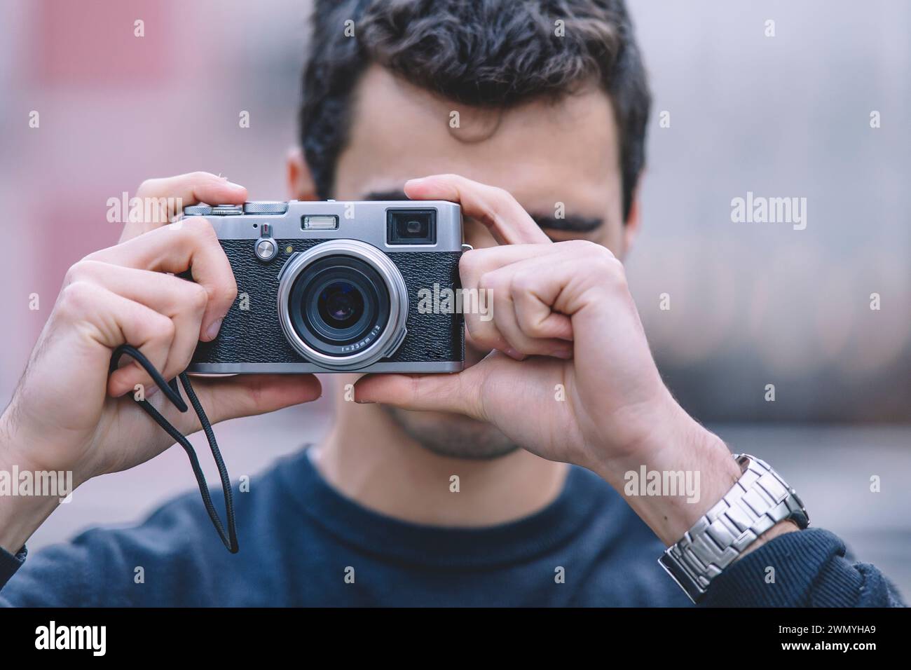Young man capturing a moment with a vintage camera, focus on camera ...