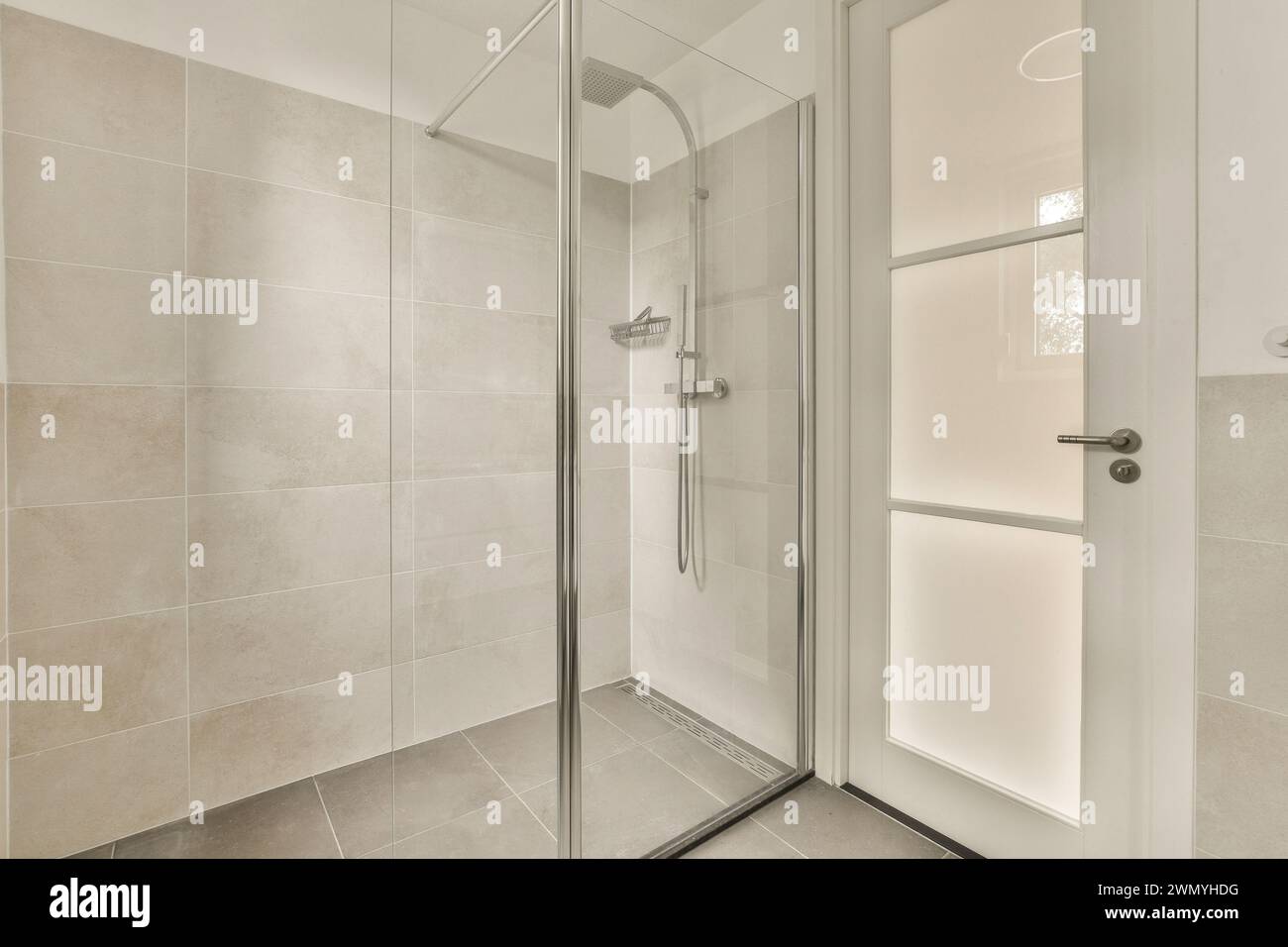 A clean, modern bathroom featuring a glass shower cubicle with beige ...
