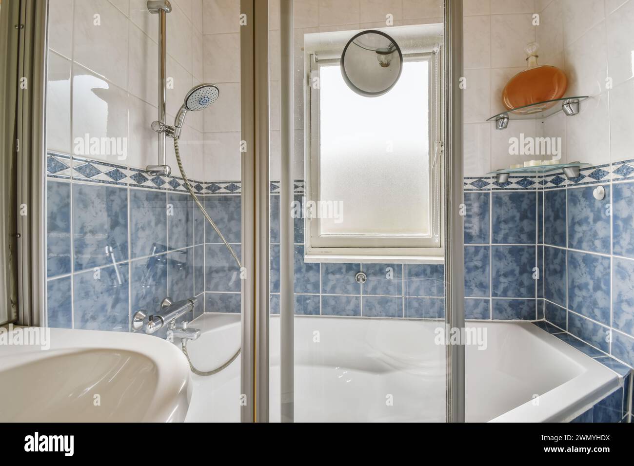 A well-lit bathroom featuring white fixtures and blue tiles Stock Photo ...