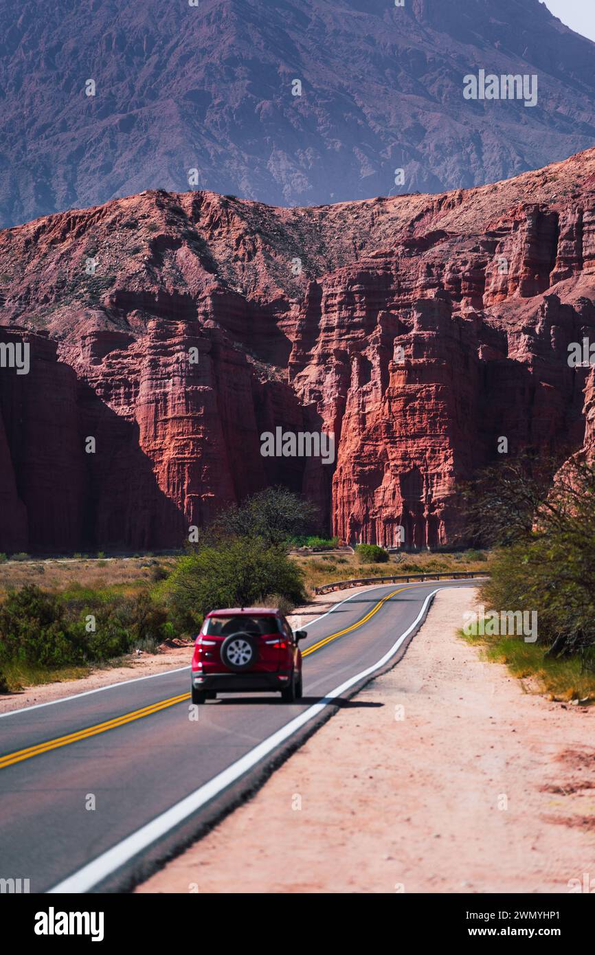Red SUV driving on a highway bending through the red rock cliffs of Los ...