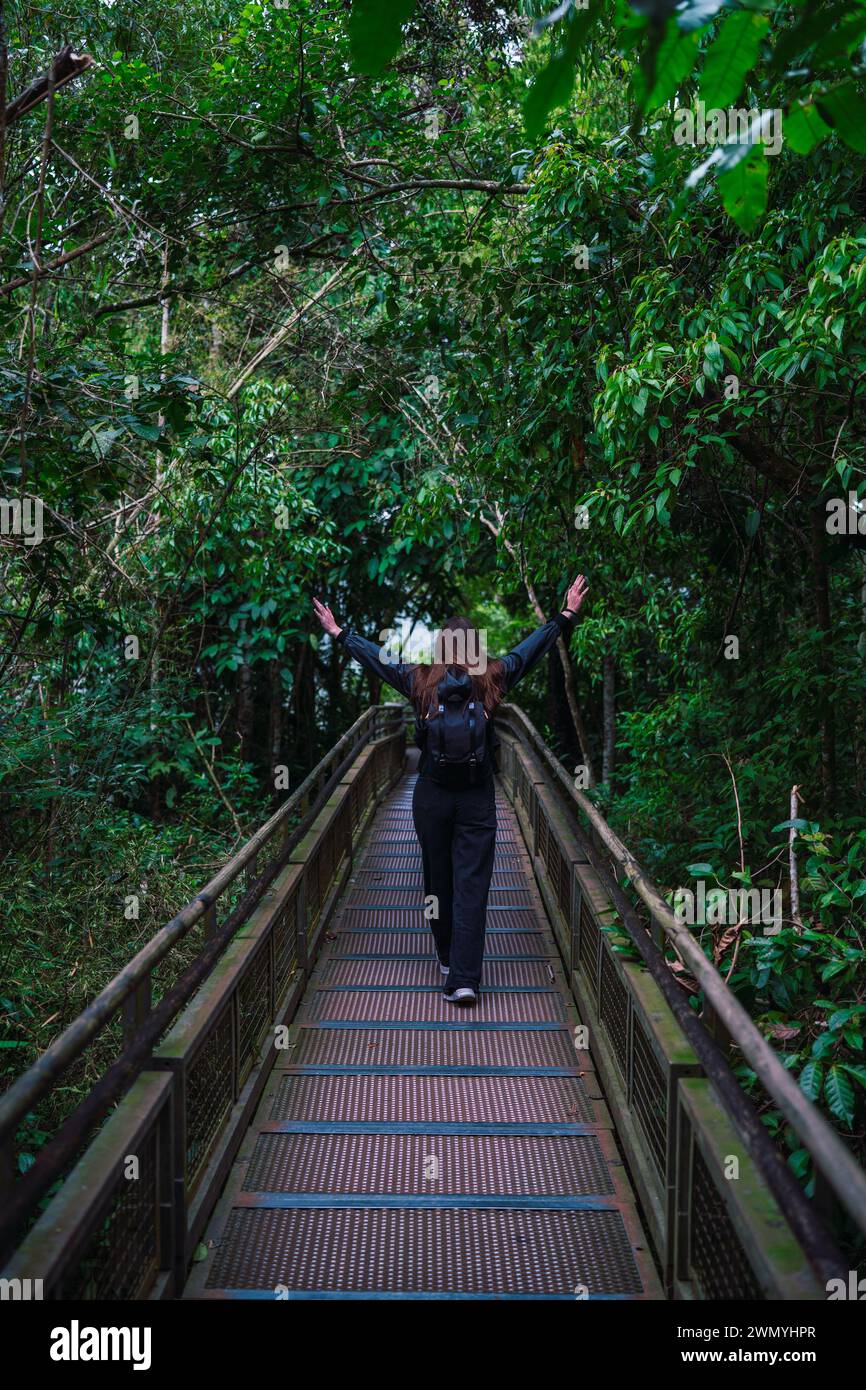 A traveler walks along a metal pathway surrounded by lush greenery in ...