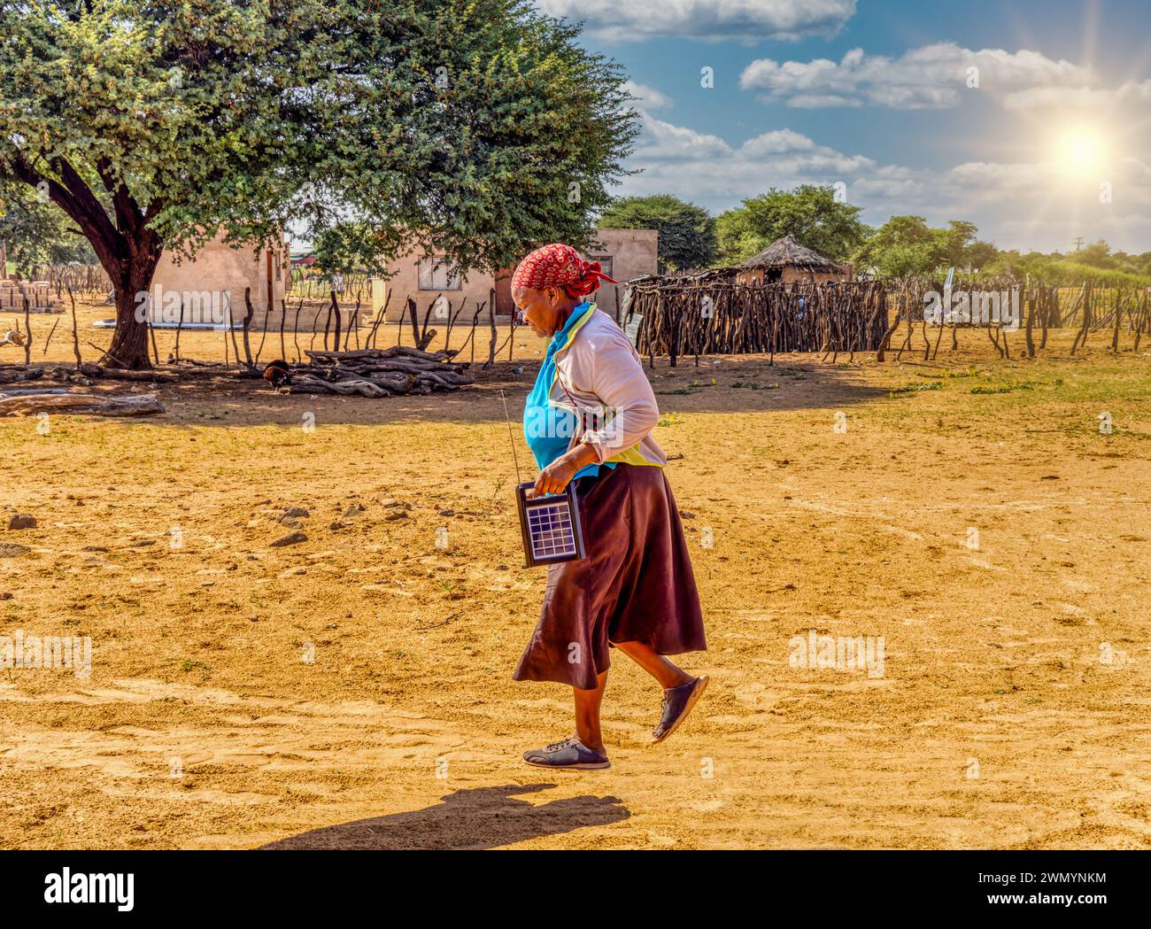 village old african woman using a solar panel with radio, to recharge ...