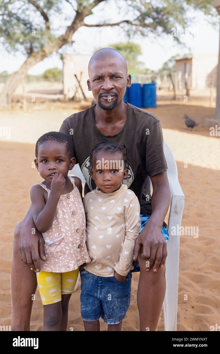 african village together with two of his daughters sited on a chair in ...