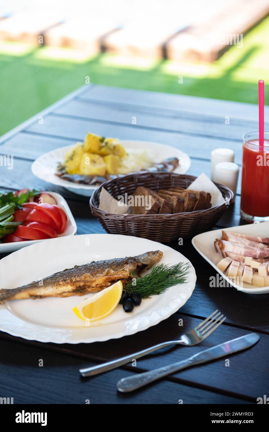 Fried grayling fish on a plate with any appetizers on swimming pool ...