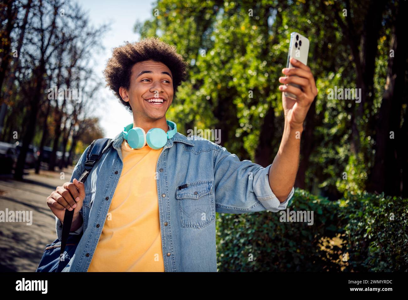 Photo of cheerful positive guy wear denim jacket earphones tacking ...