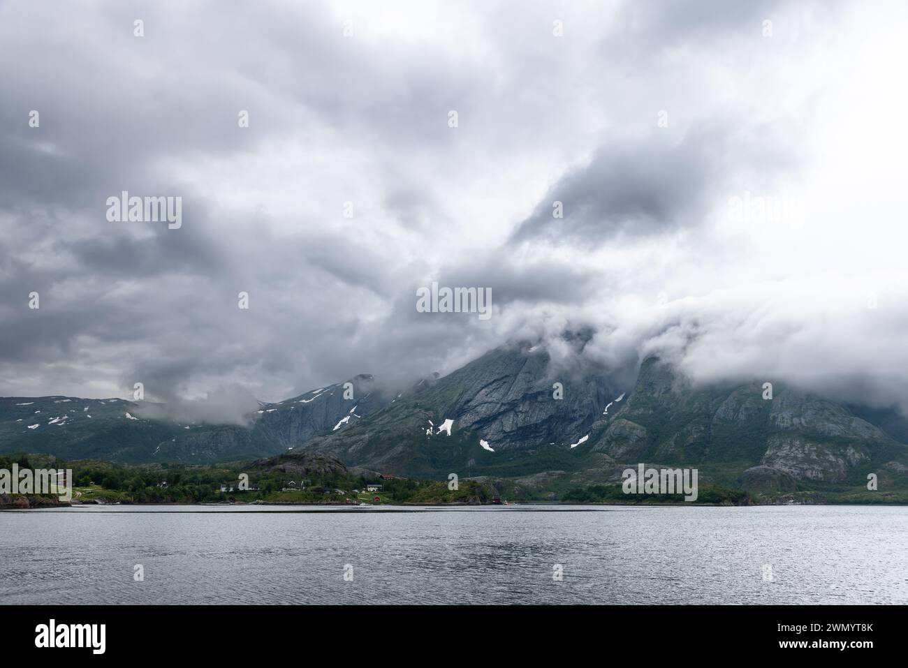 A Norwegian fjord scene in summer, where low-hanging clouds blend with ...