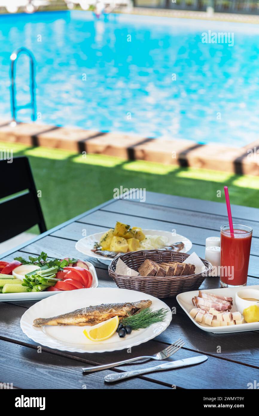 Fried grayling fish on a plate with any appetizers on swimming pool ...