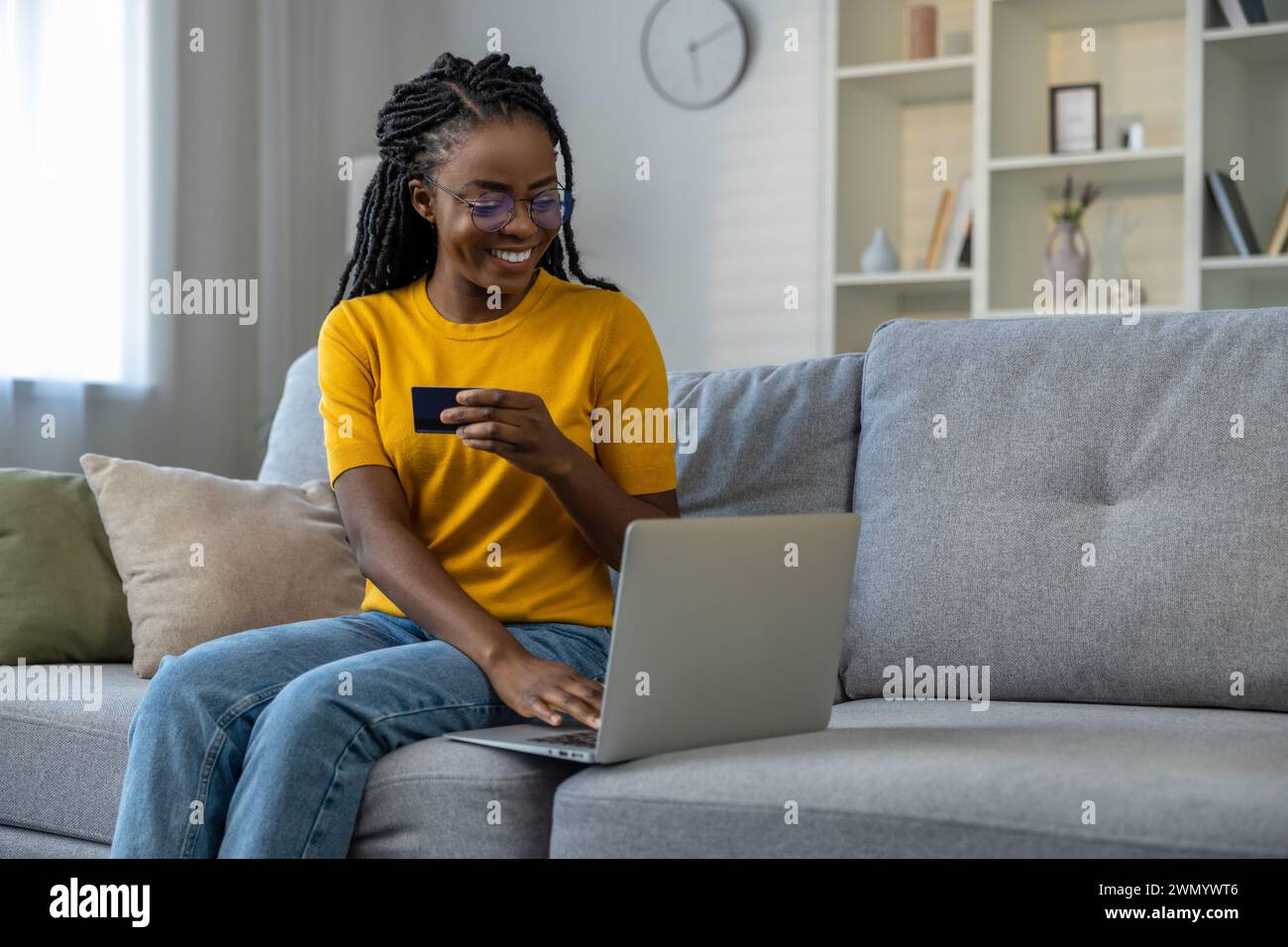 Young dark-skinned woman looking contented while making online payment ...