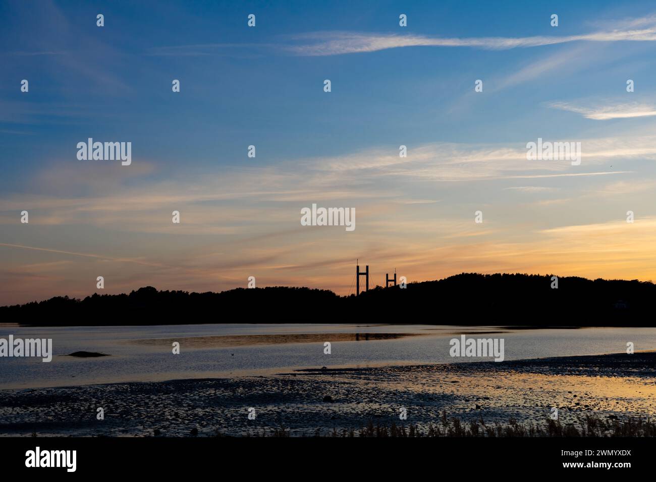 Sunset with reflections in water and silhouette of treeline. Bridge ...