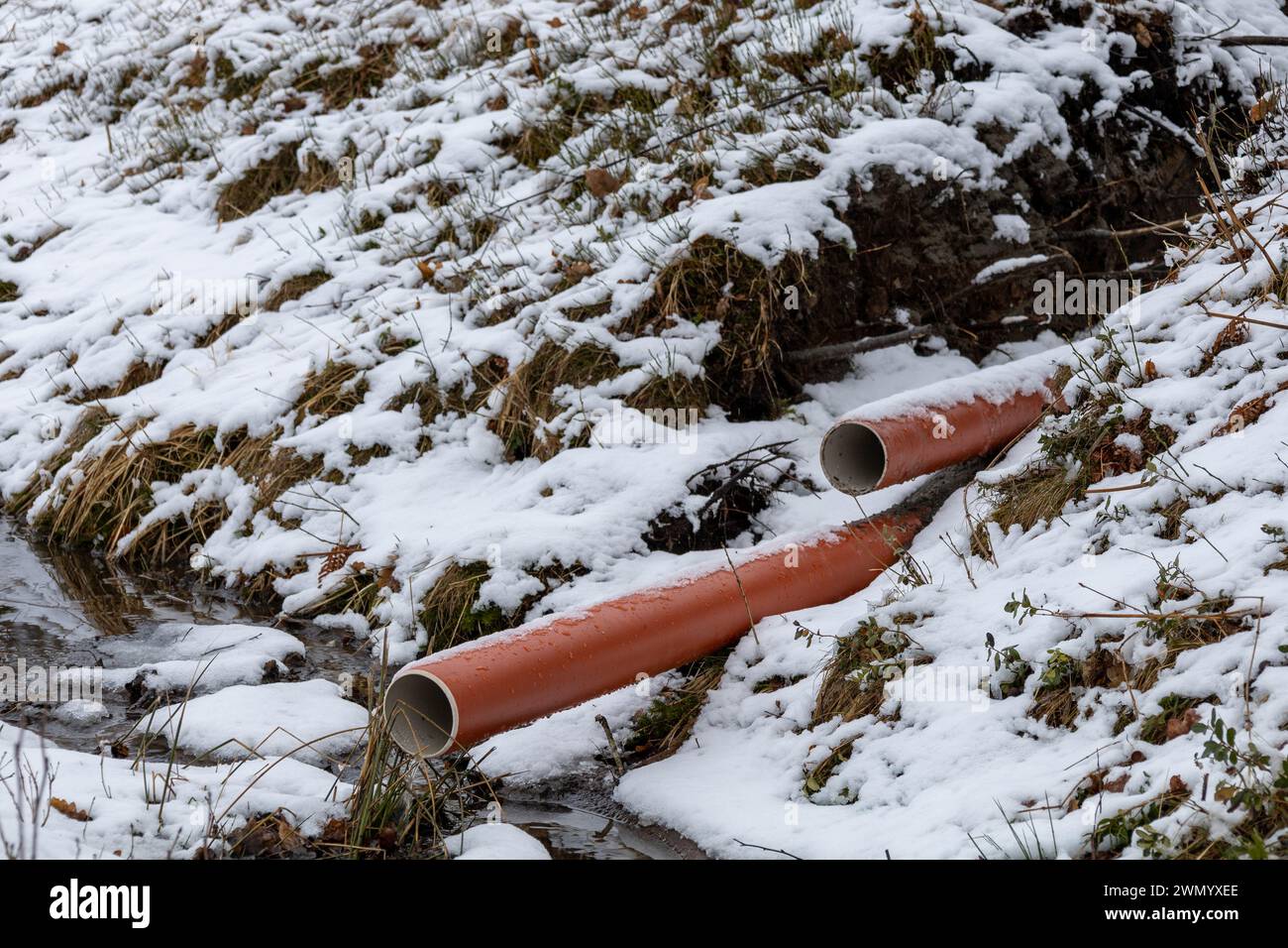 Drain piping for home sewage in a ditch in winter with snow on the ...
