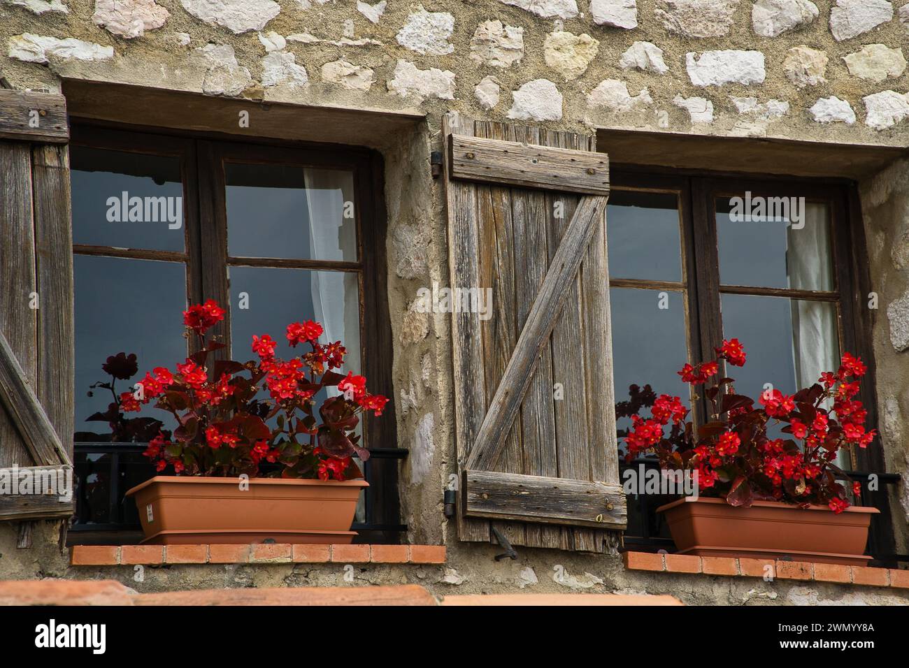 Beautiful red flower pots on display at window of an old house in a ...